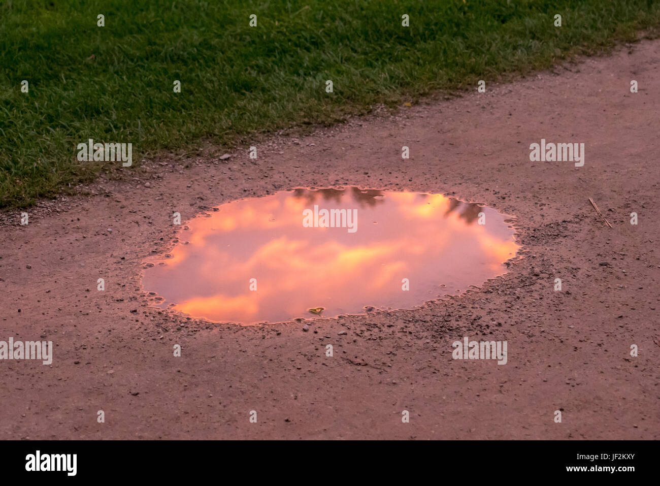 Reflection of sunset in puddle on track Stock Photo - Alamy