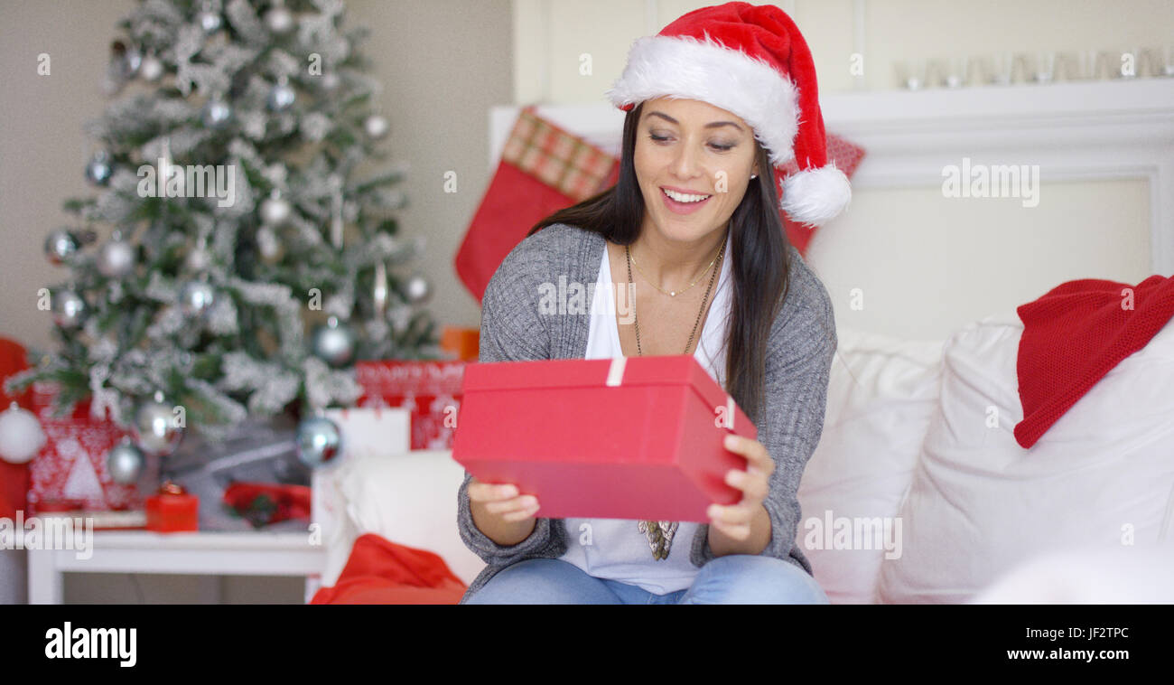 Excited young woman opening a Christmas gift Stock Photo - Alamy