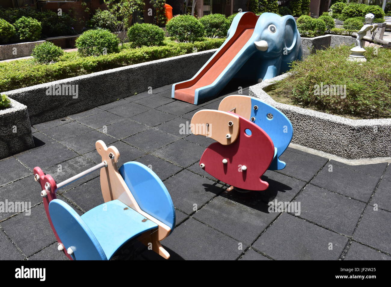 Community playground with blue elephant slide and rocking toys in ...