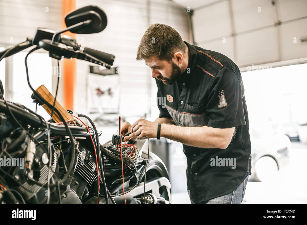 Motorcycle mechanic repairing electronics sports black bike. Handsome ...