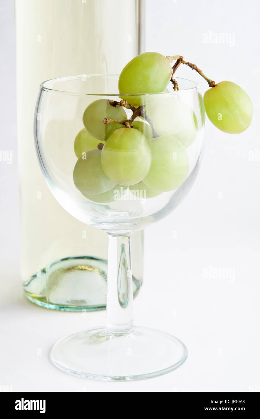 A wine glass filled with white (green) grapes, standing in front of a ...