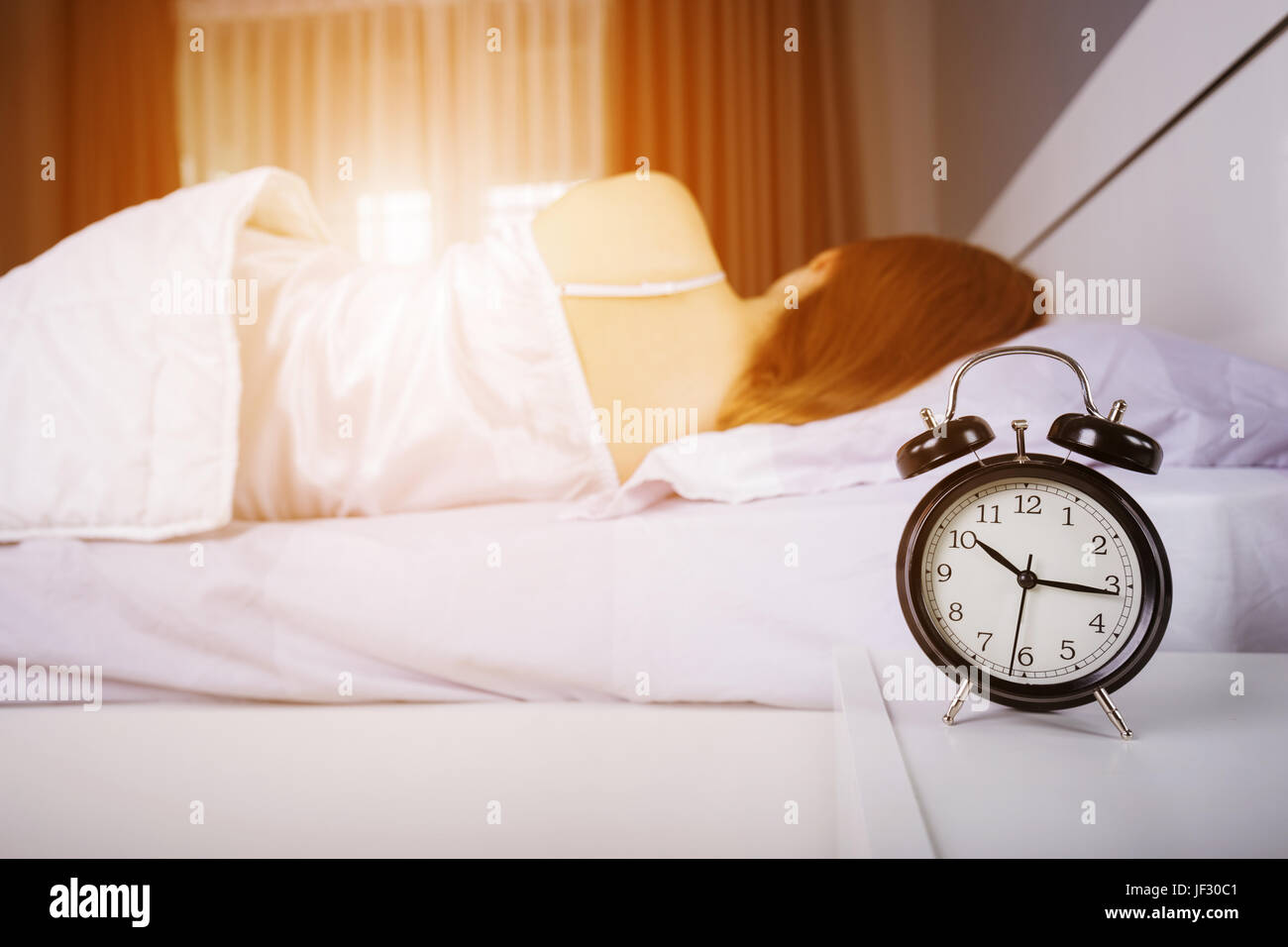 clock show 10 am. and woman sleeping on bed with sunlight in the ...