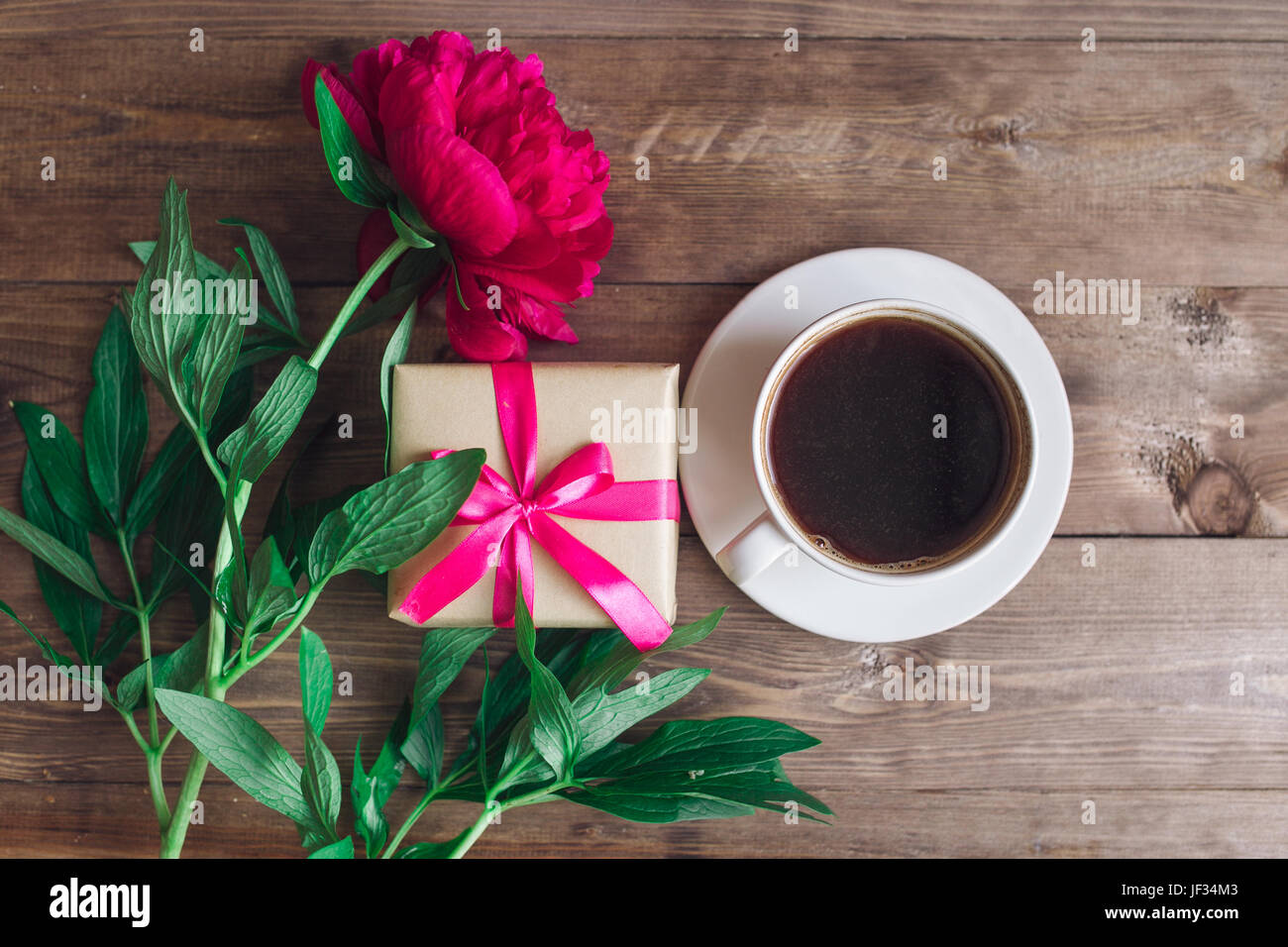 A cup of coffee , pink peonies pattern and gift box on wooden ...