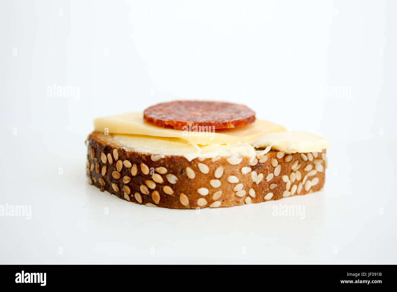A sandwich with buttered cheese and sausage bread with sesame seeds ...