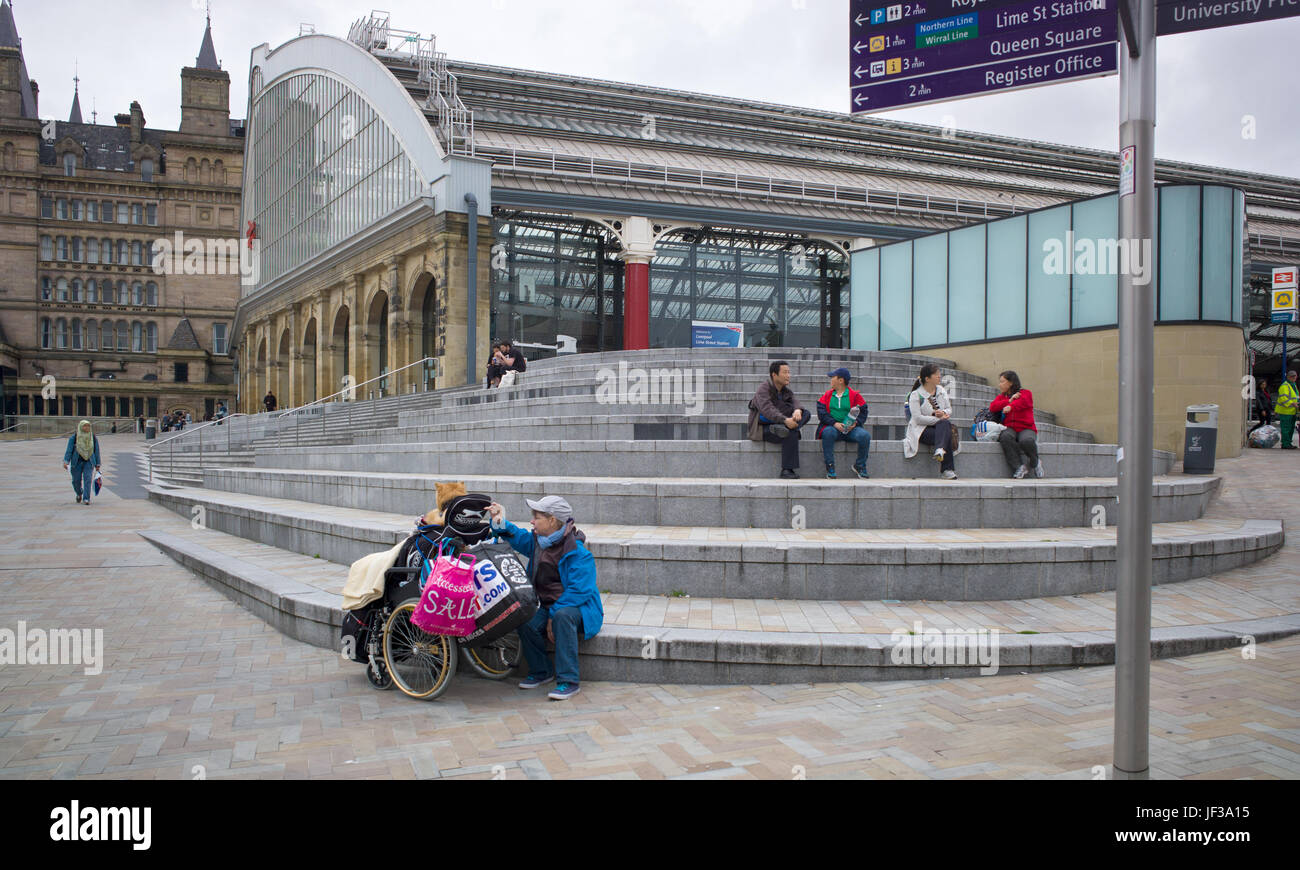 Woman with wheelchair, bags, dog, and blanket and other people on steps ...