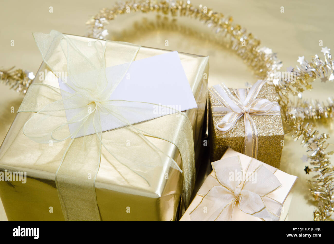 A group of Christmas gifts wrapped in gold foil paper with ribbon on a ...