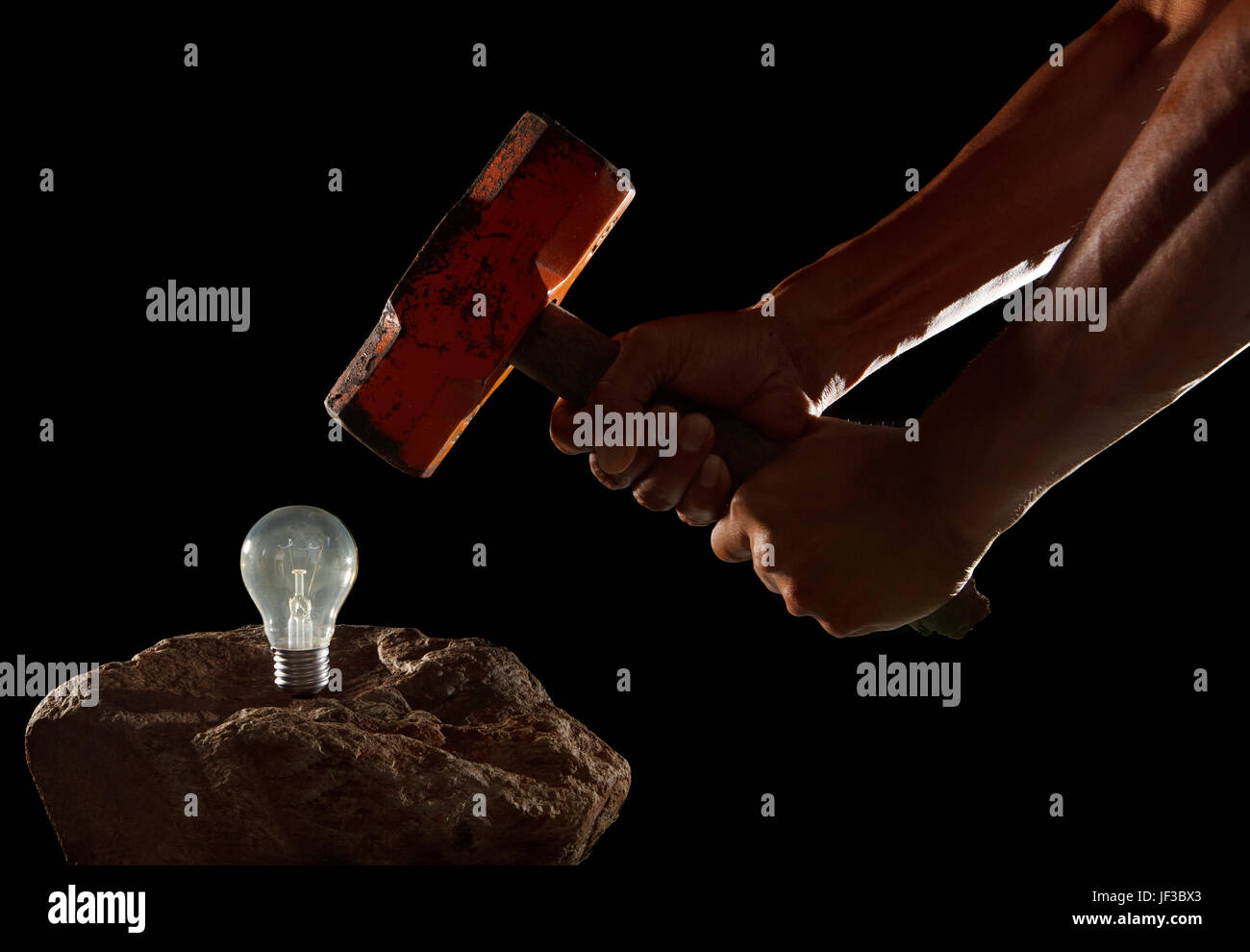 abstract of hand holding heavy hammer to breaking light bulb on the ...