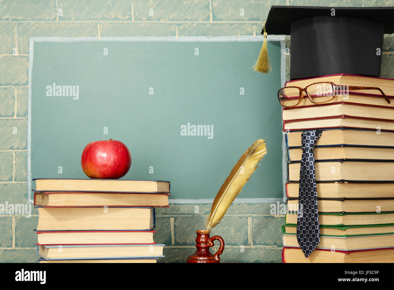 Unusual jesting teacher, books, quill pen, apple before blackboard with ...