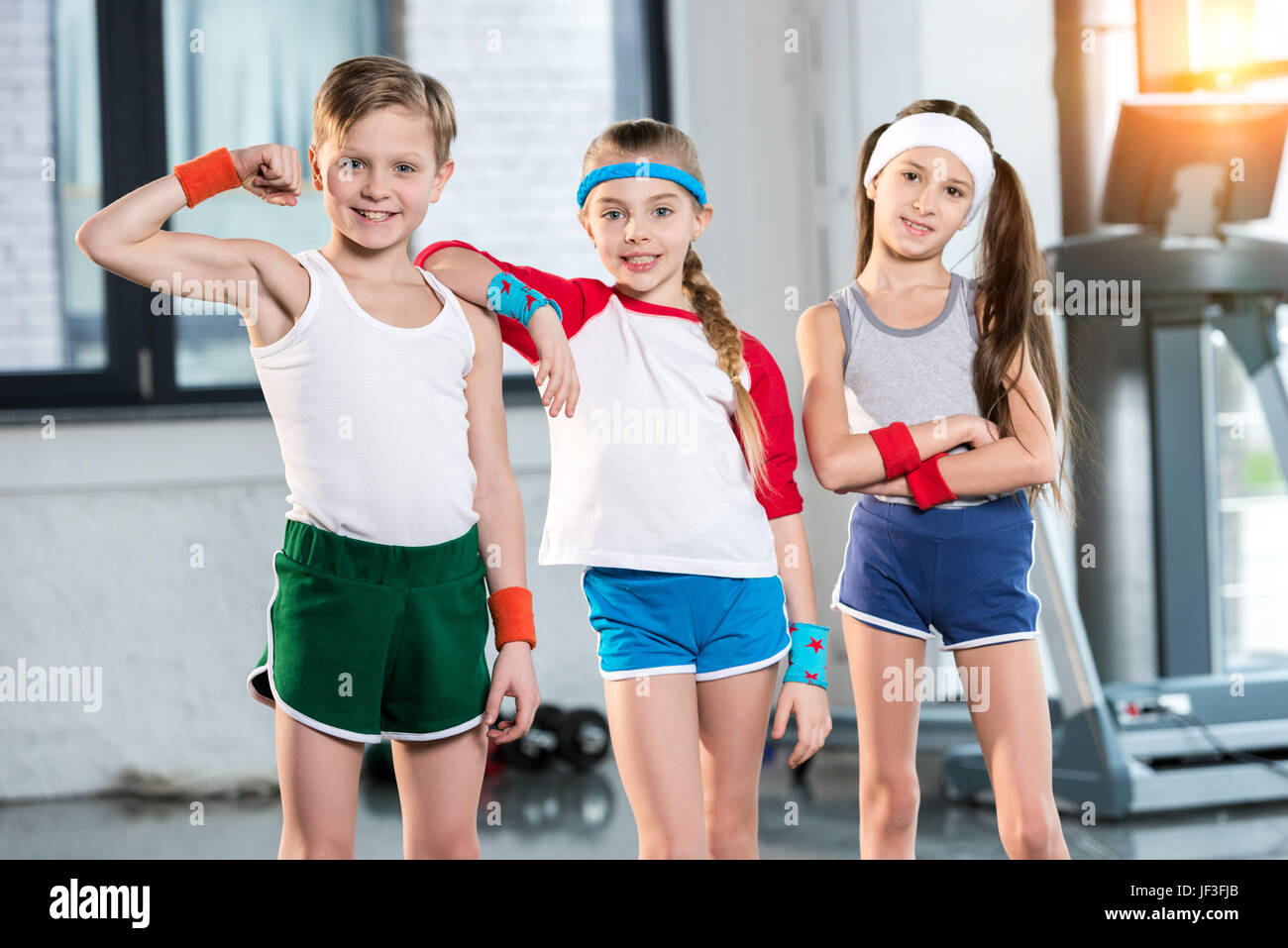 adorable kids in sportswear smiling and posing at fitness studio ...