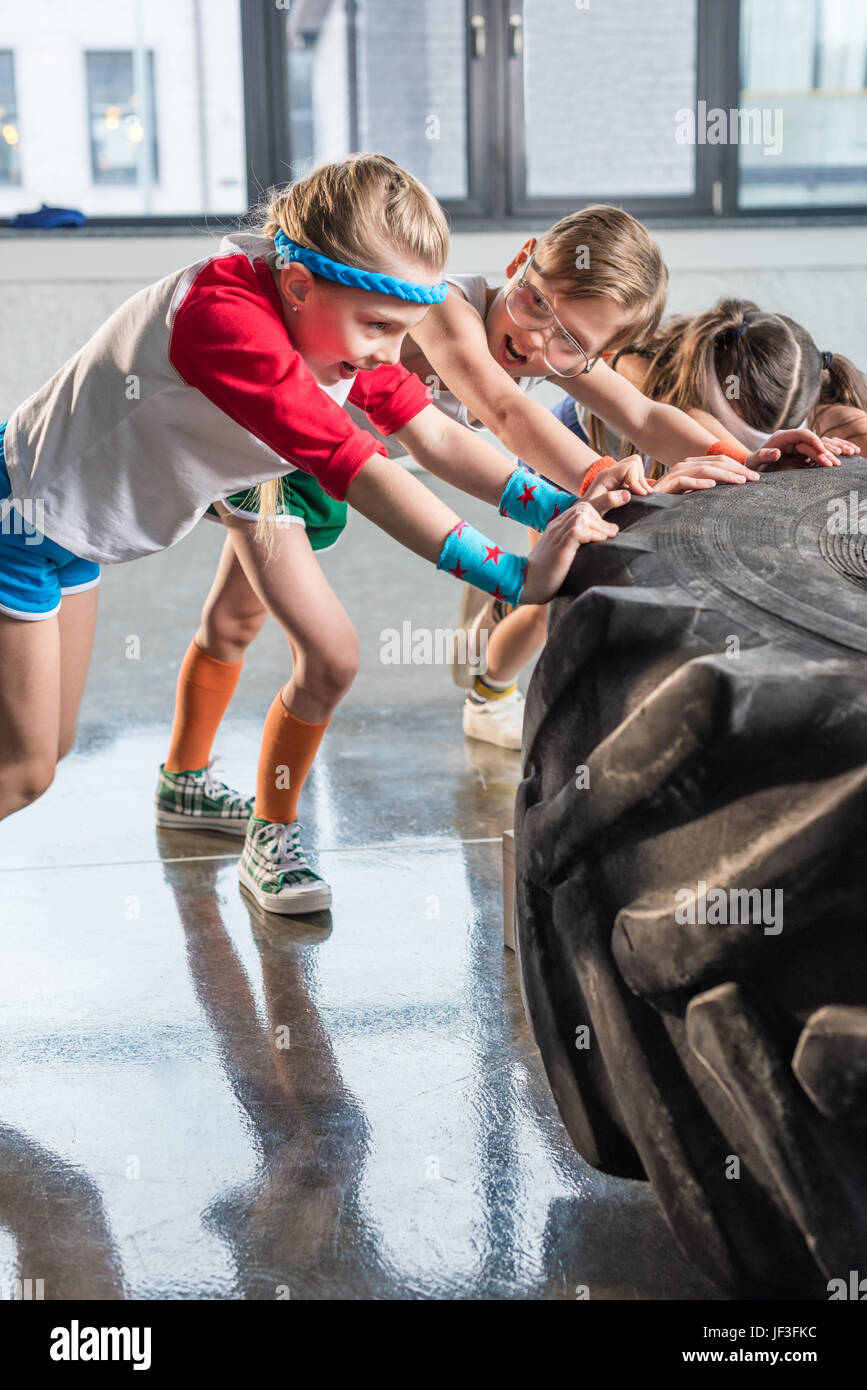 adorable kids in sportswear training with tire at fitness studio ...