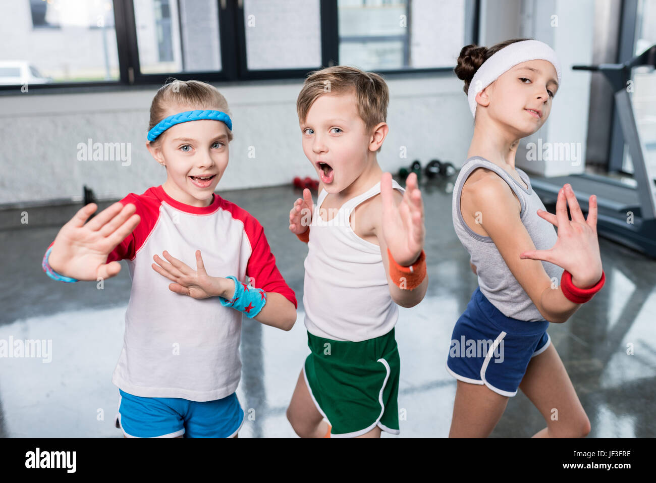 Group of little kids in sportswear exercising and posing at camera in ...
