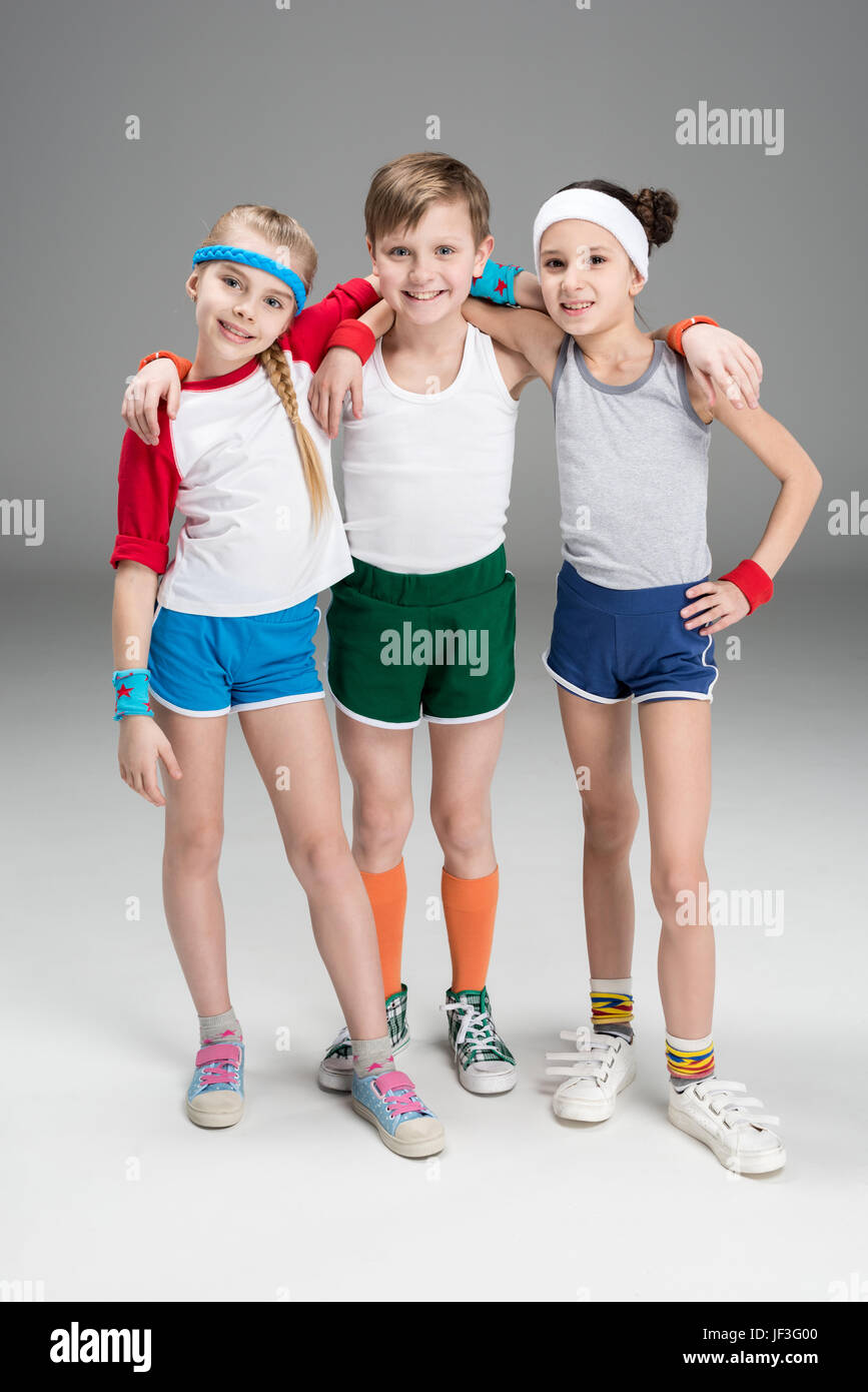 Adorable smiling sporty kids in sportswear standing together isolated ...