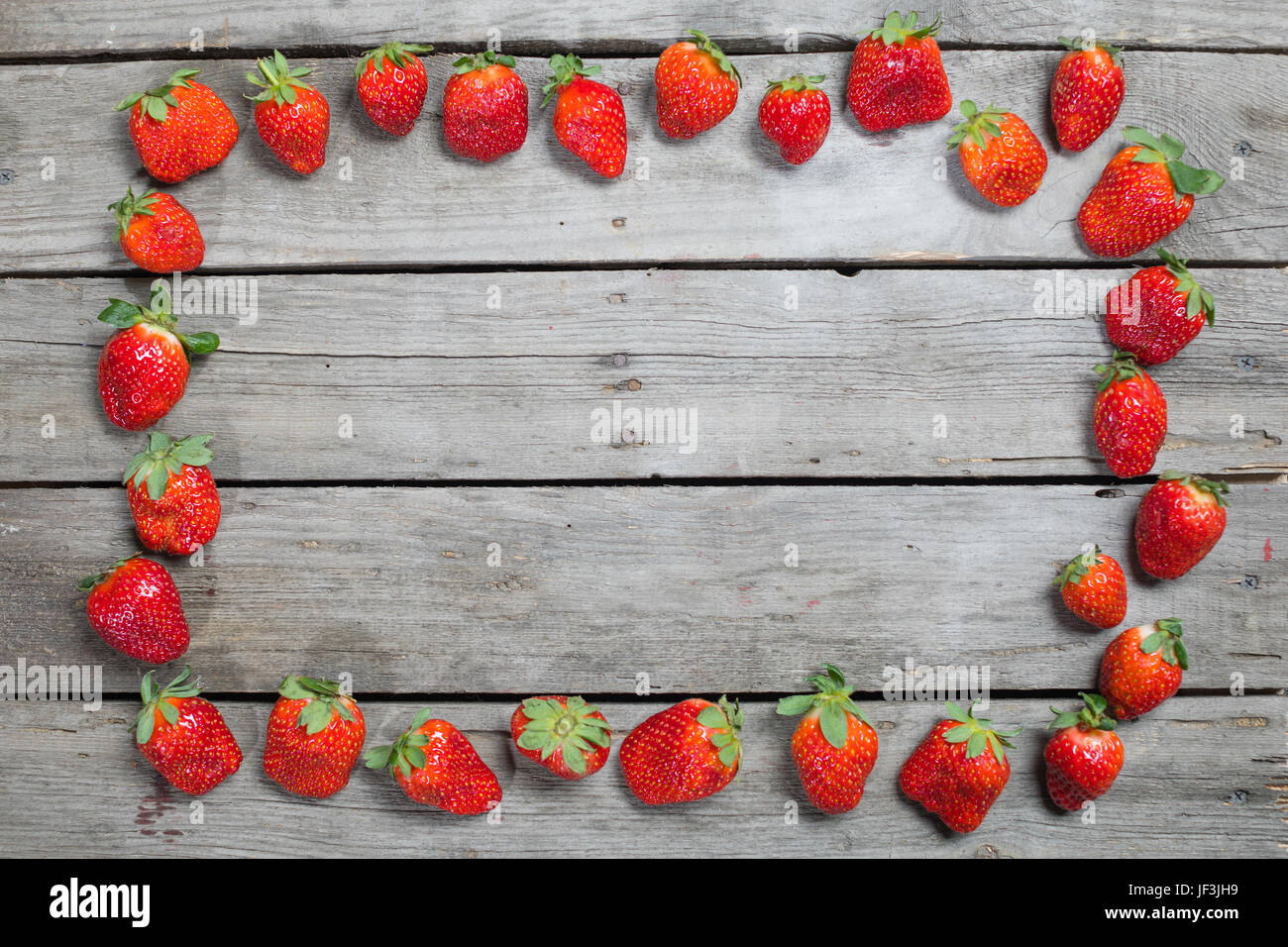 frame of fresh red strawberries on wooden tabletop with copy space ...