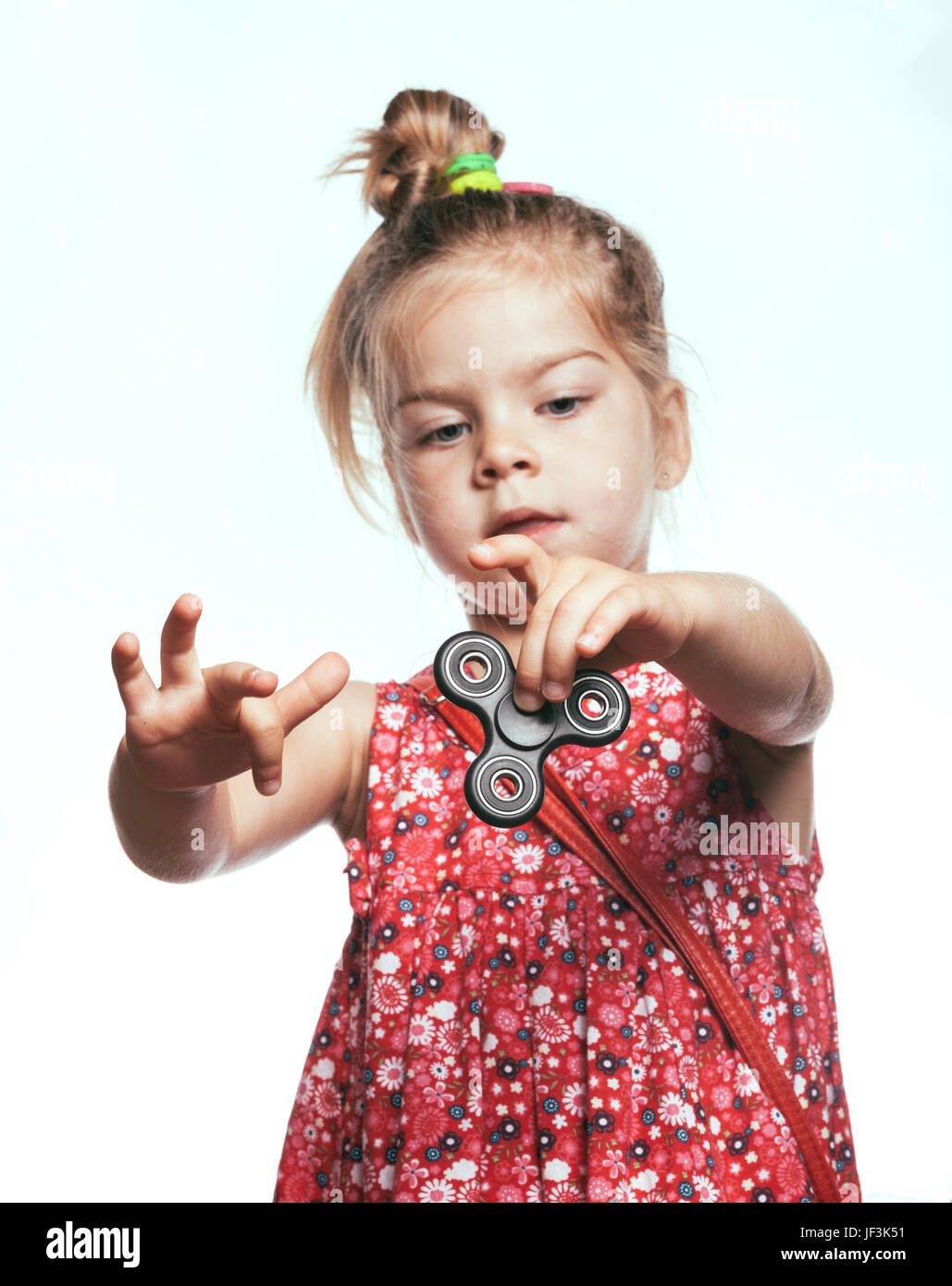 Little girl playing with fidget spinner, on white background. faded ...