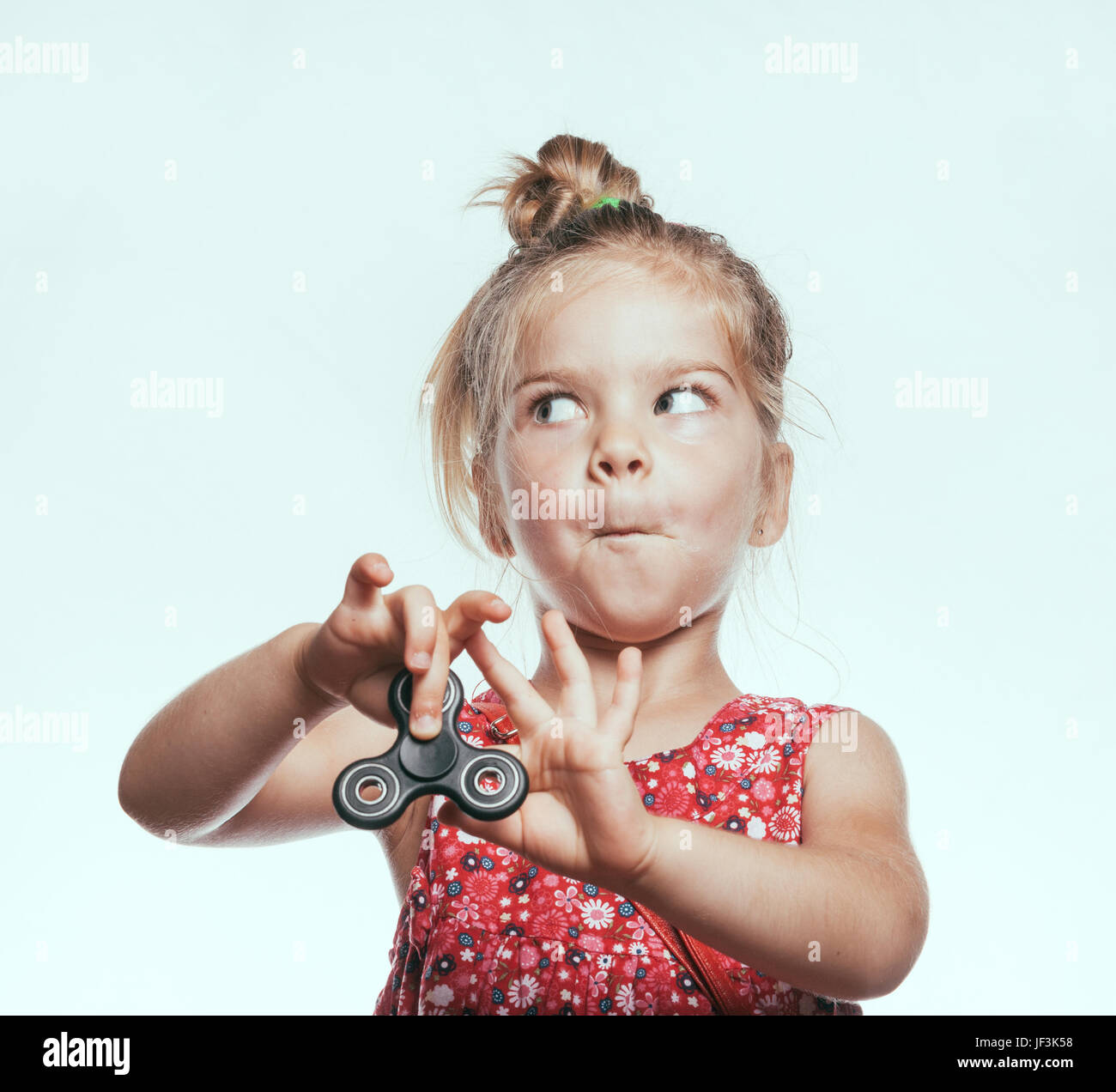 Little girl playing with fidget spinner, on white background. faded ...
