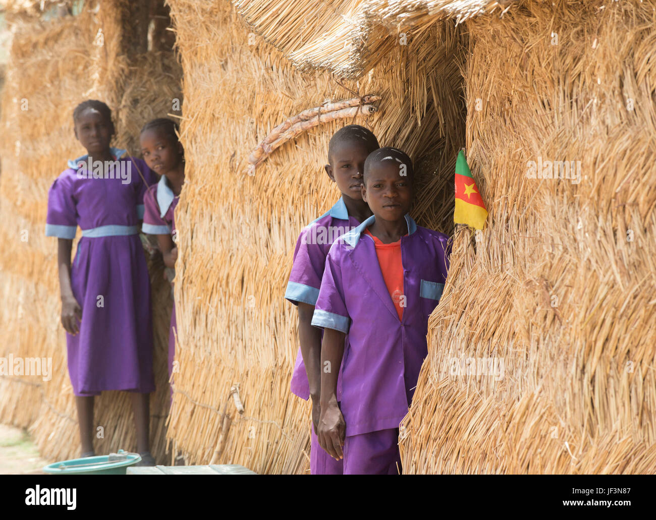 Students stand outside their primary school, a thatched hut with three ...