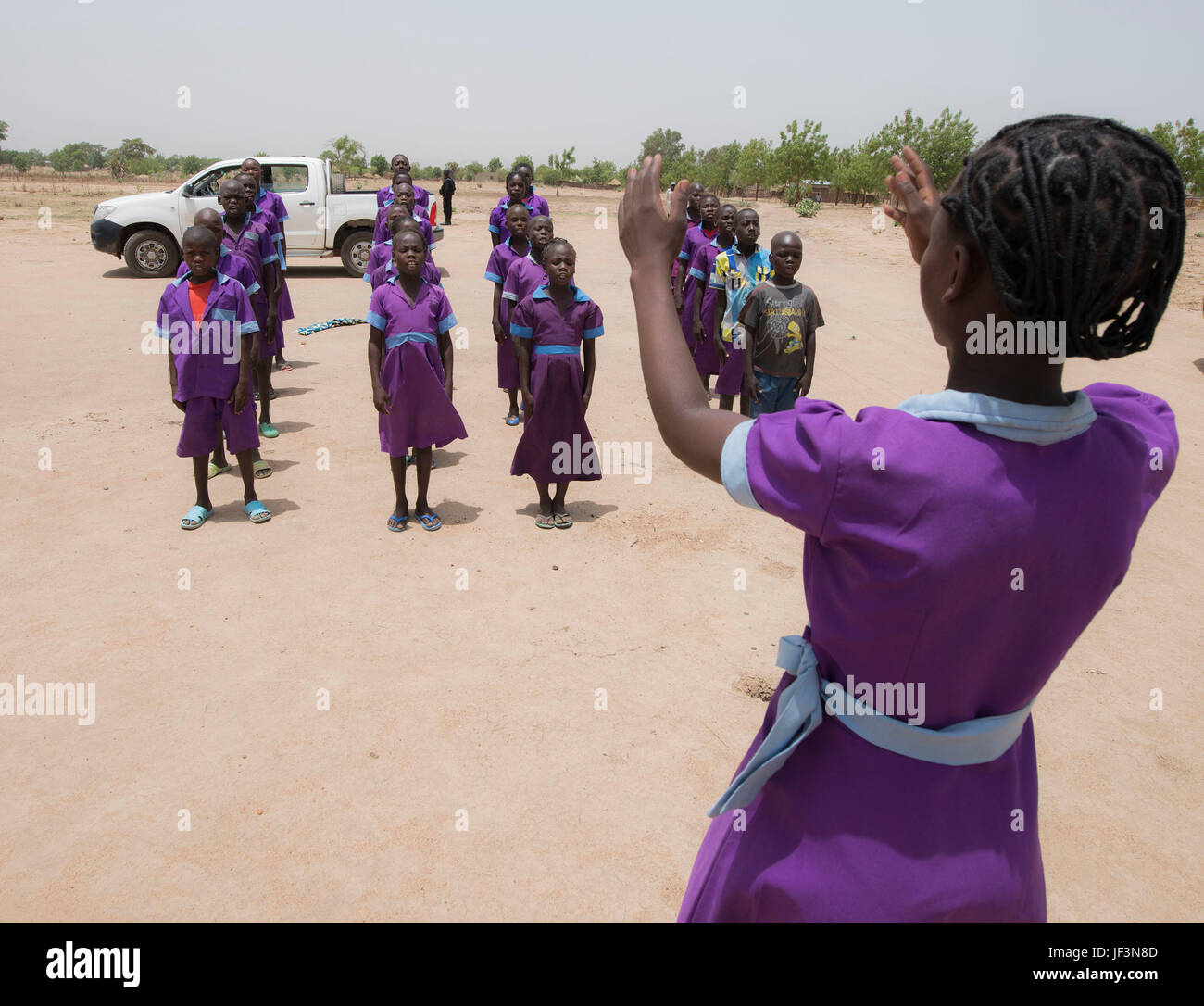 Rows of students welcome an Army civil affairs team with a song before ...
