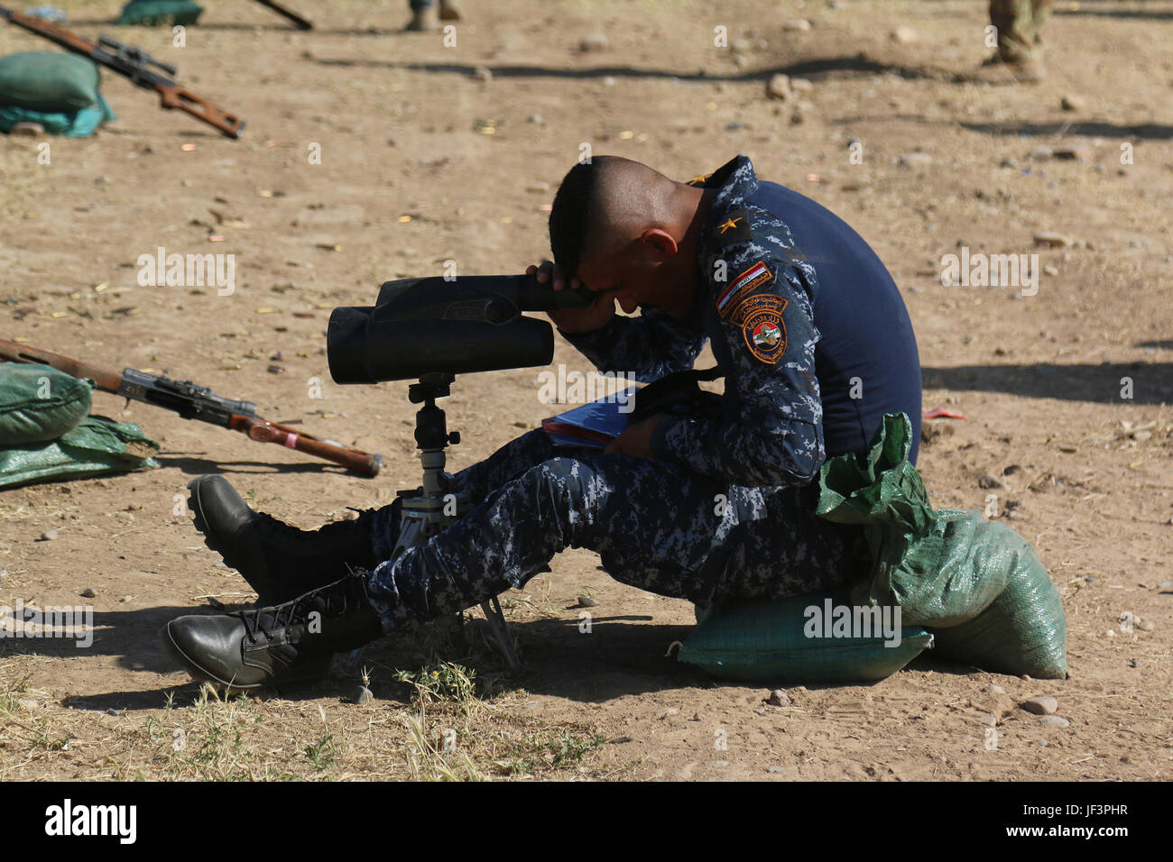 A member of the Iraqi Federal Police looks through a spotter scope ...