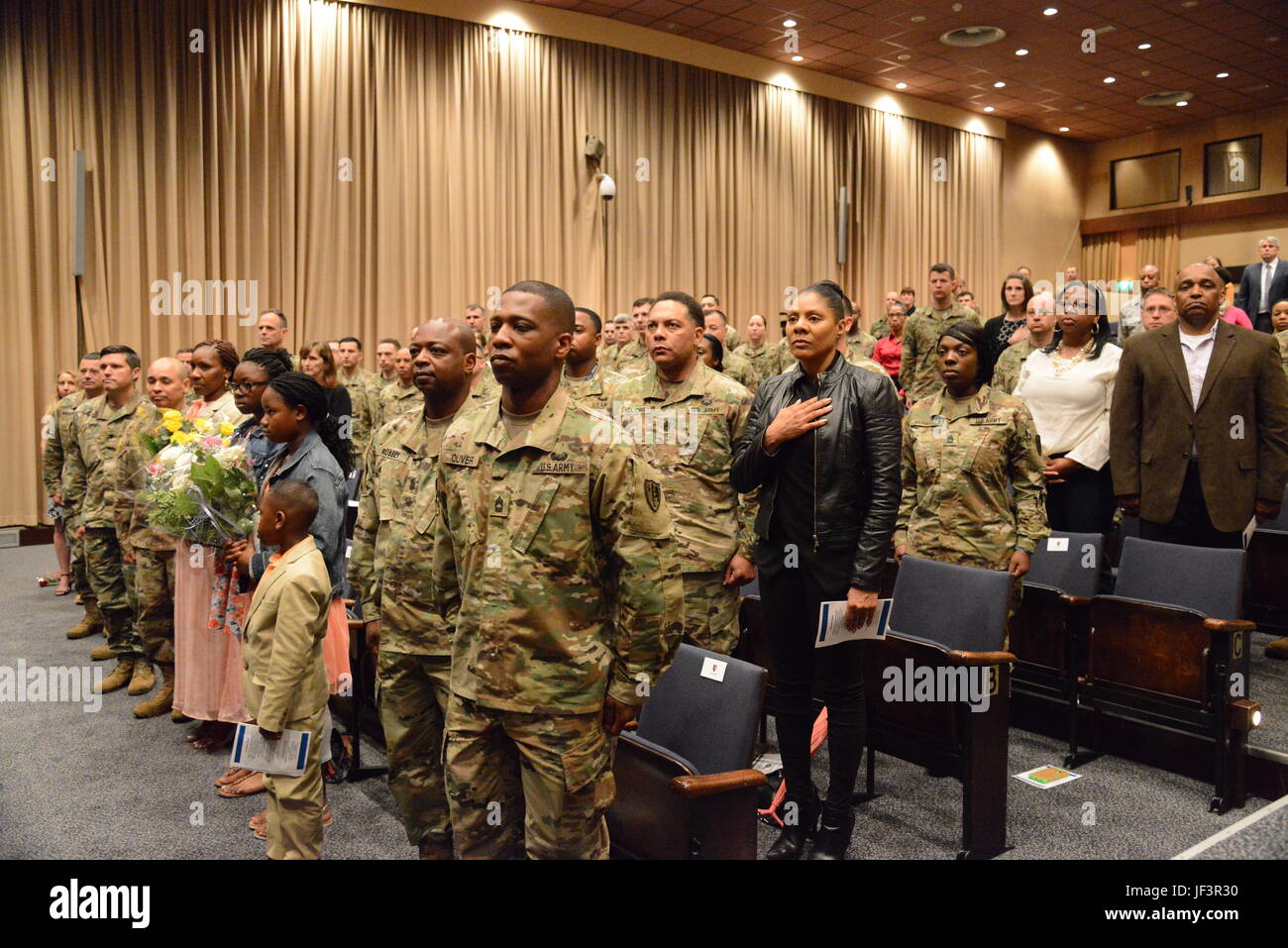 U.S. Soldiers and civilian employees, stand at attention for the ...