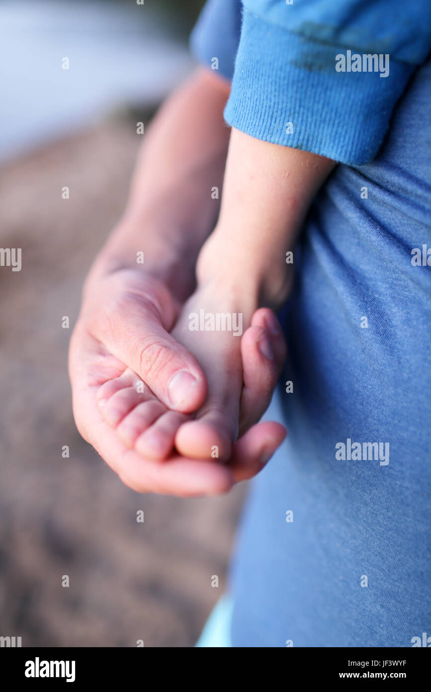 Mans hand holding childs foot Stock Photo - Alamy