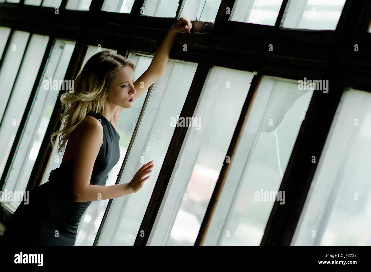 Beautiful girl looking out of a window Stock Photo - Alamy