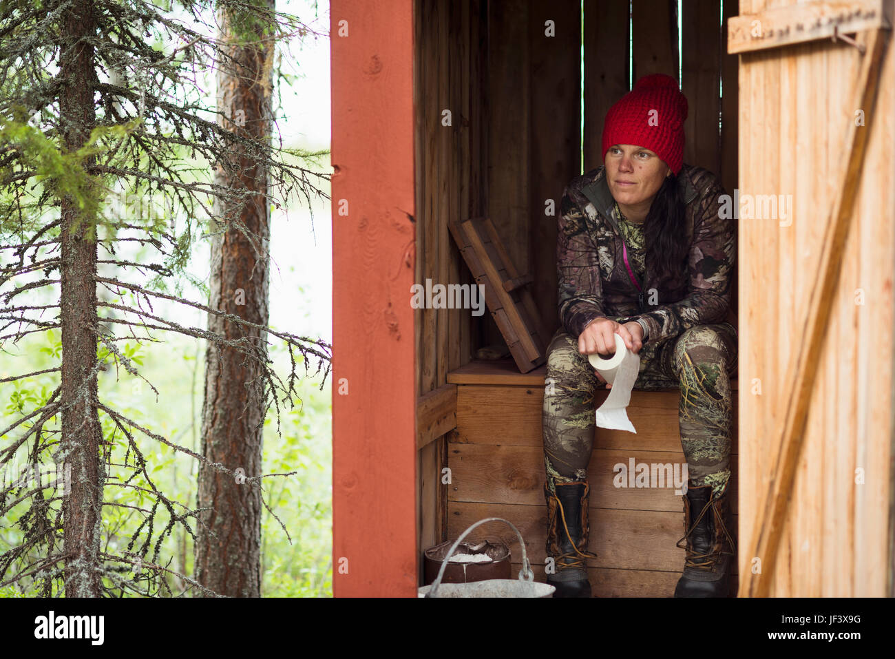 Woman sitting in wooden outhouse Stock Photo - Alamy
