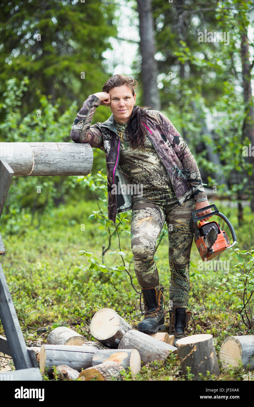 Woman holding chainsaw and looking at camera Stock Photo - Alamy