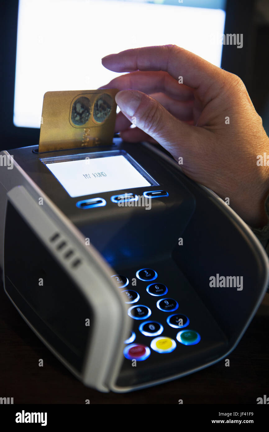 Hand putting bank card into card reader Stock Photo - Alamy