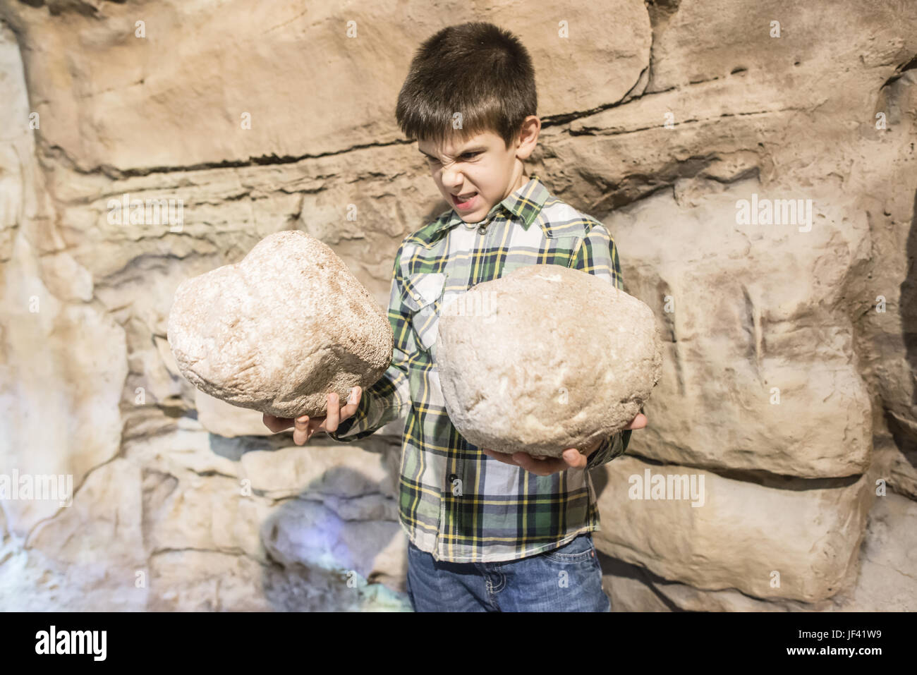 Strong child holds heavy stone Stock Photo - Alamy