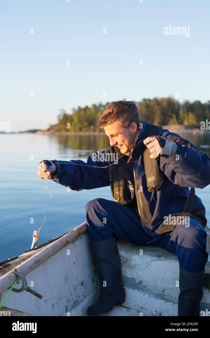 Young man fishing on boat Stock Photo - Alamy