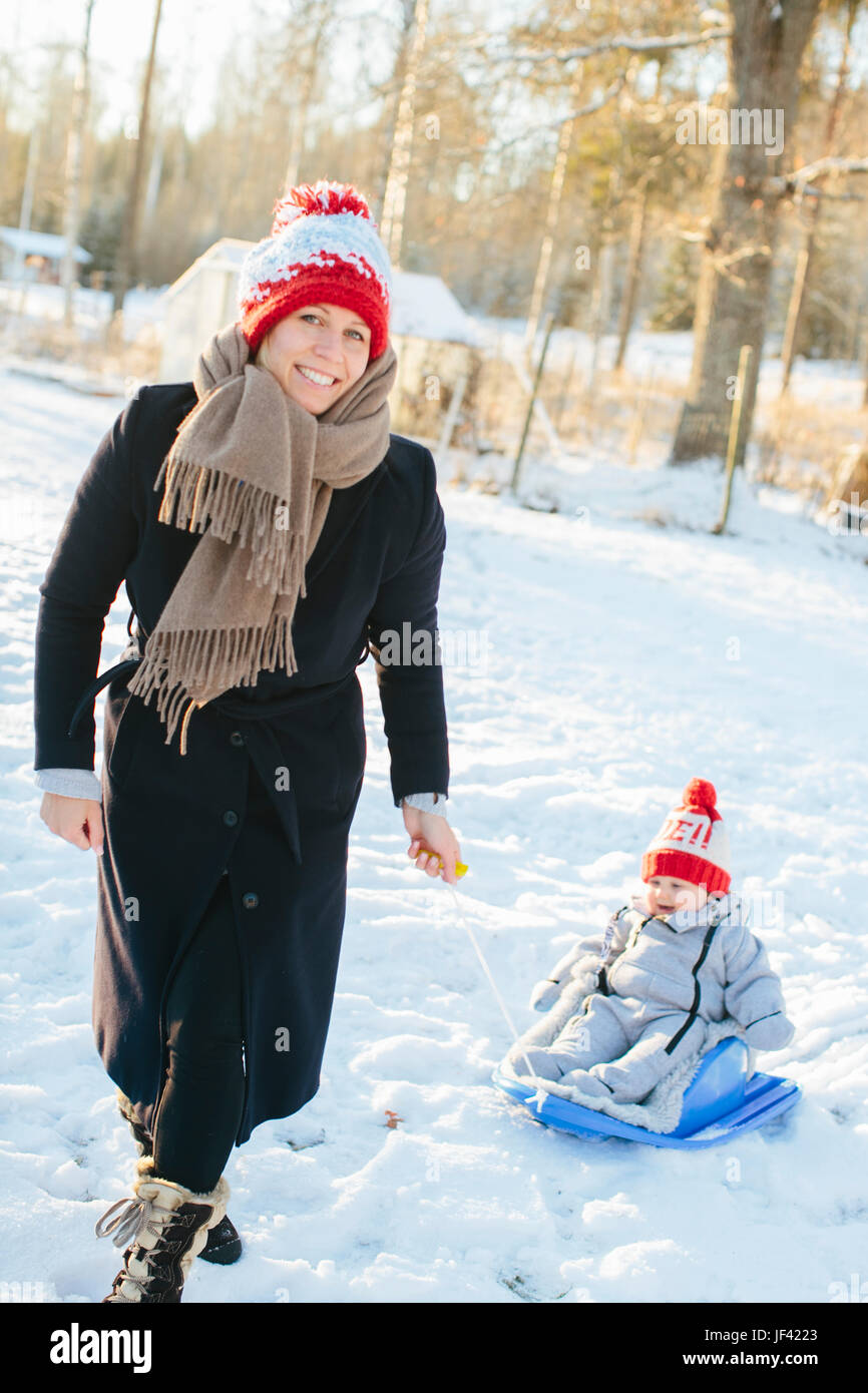 Mother pulling baby on sledge Stock Photo - Alamy