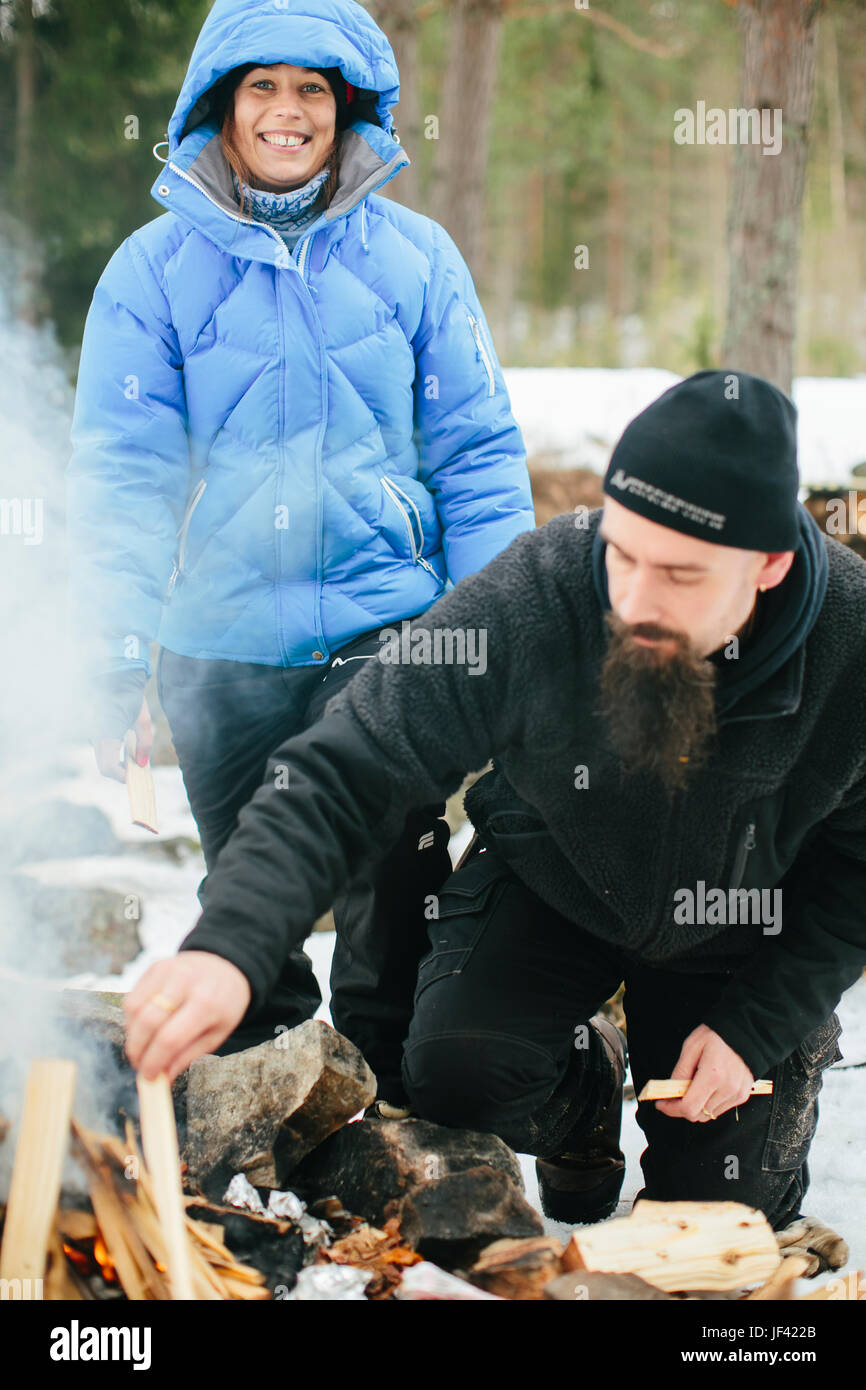 Man making campfire, woman on background Stock Photo - Alamy