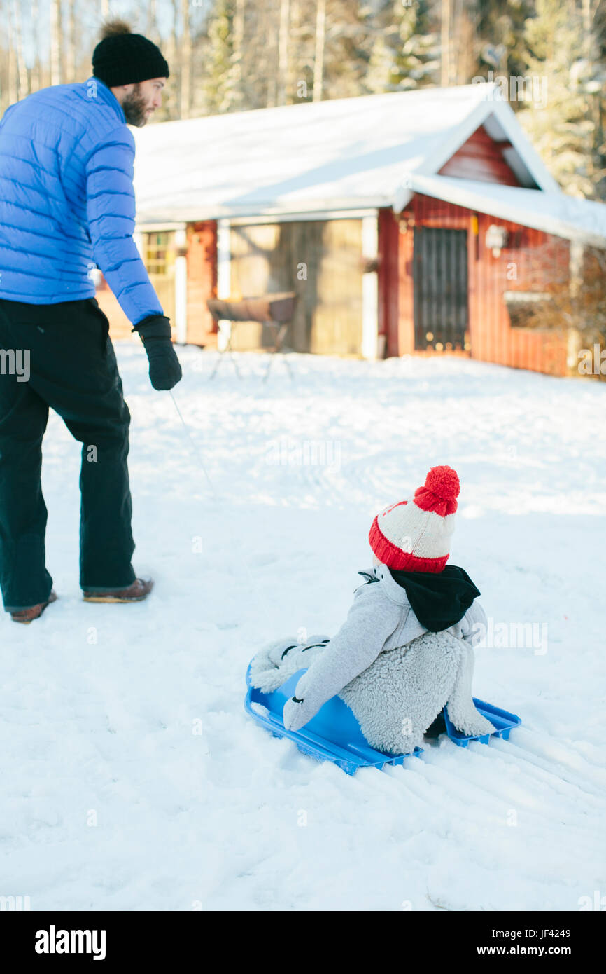 Father pulling baby on sledge Stock Photo - Alamy
