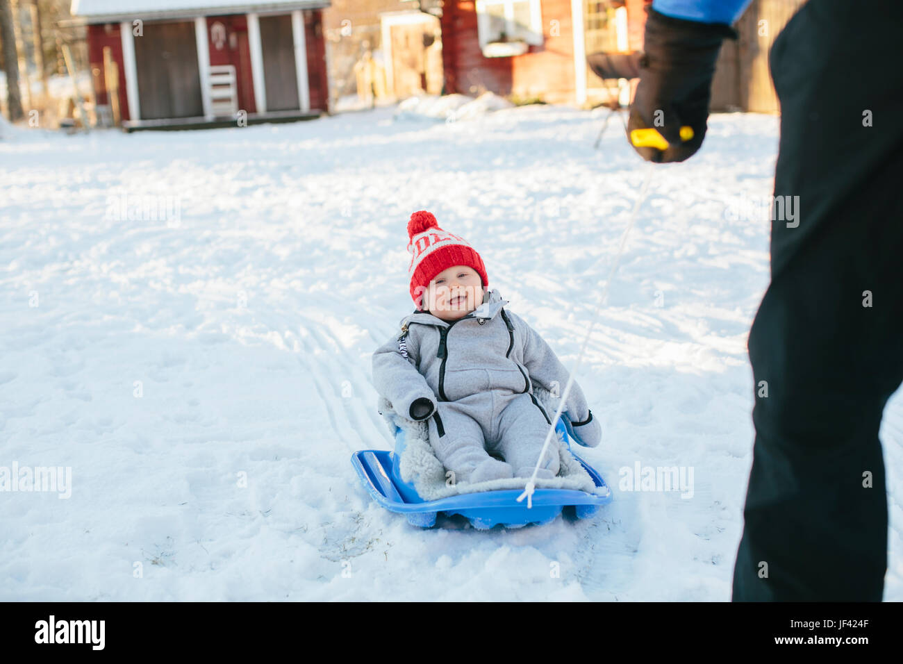 Parent pulling baby on sledge Stock Photo - Alamy