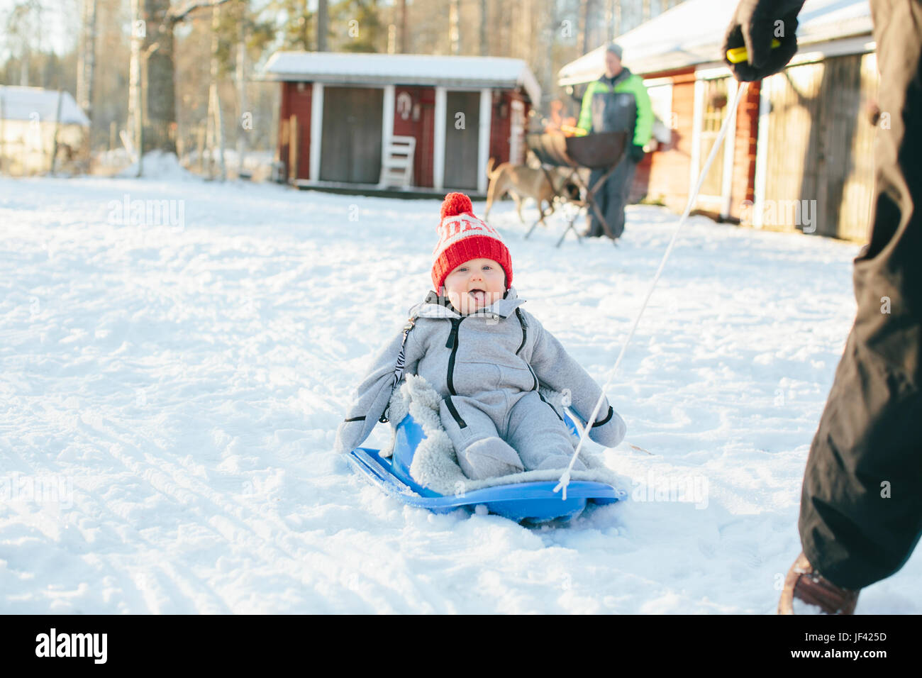 Parent pulling baby on sledge Stock Photo - Alamy