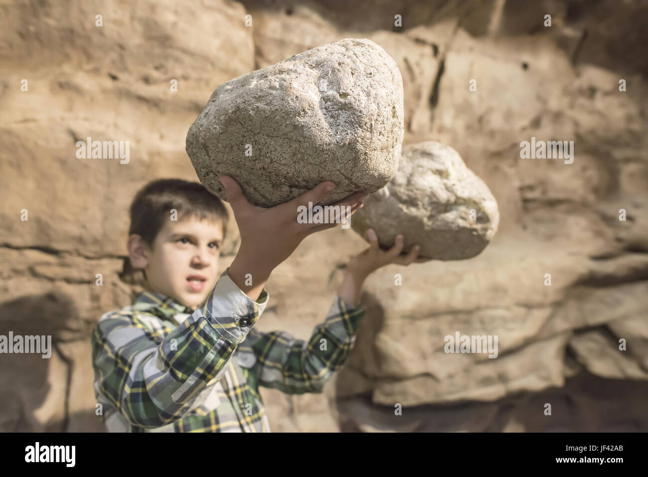 Strong child holds heavy stone Stock Photo - Alamy