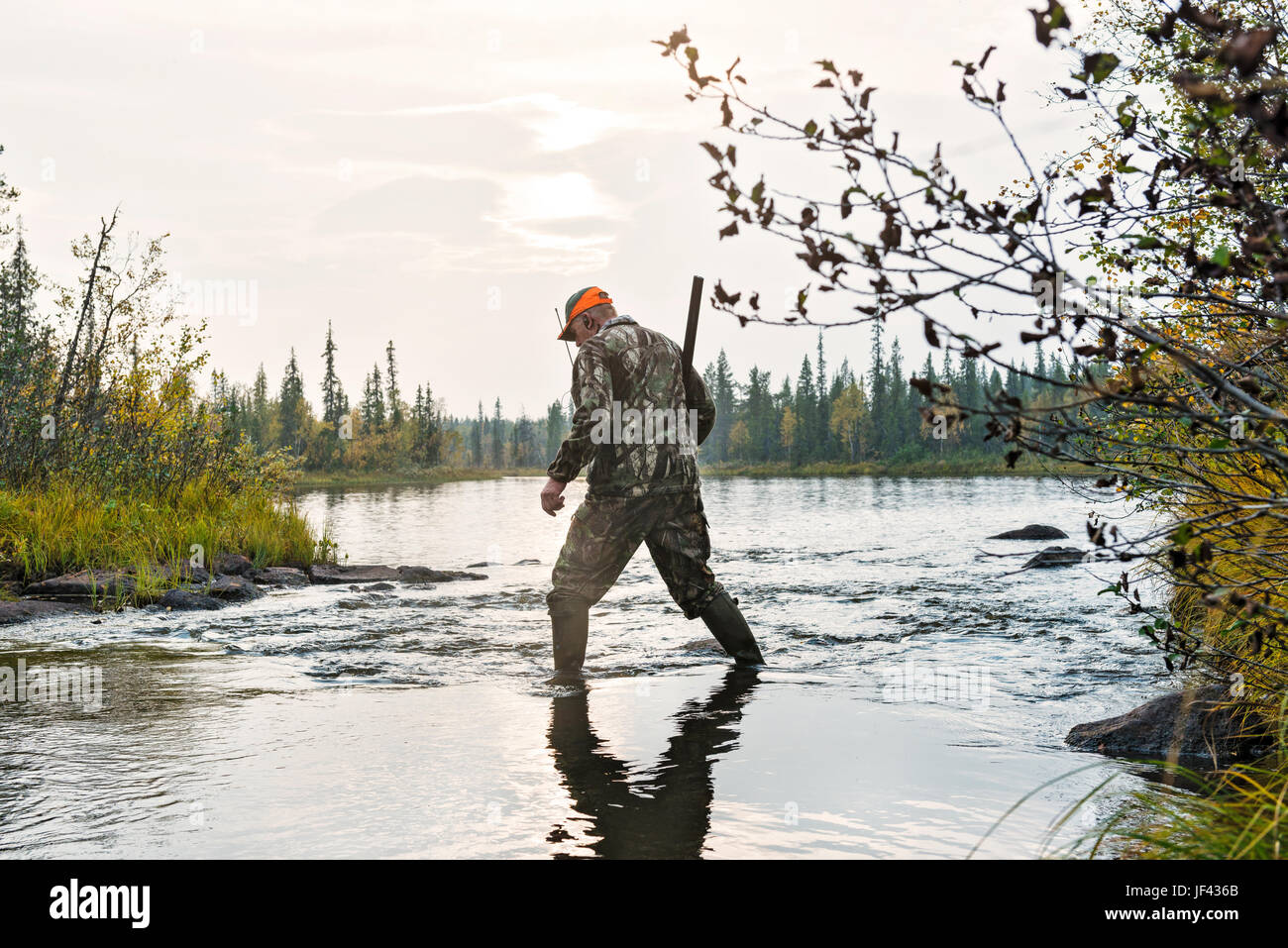 Hunter crossing river Stock Photo - Alamy