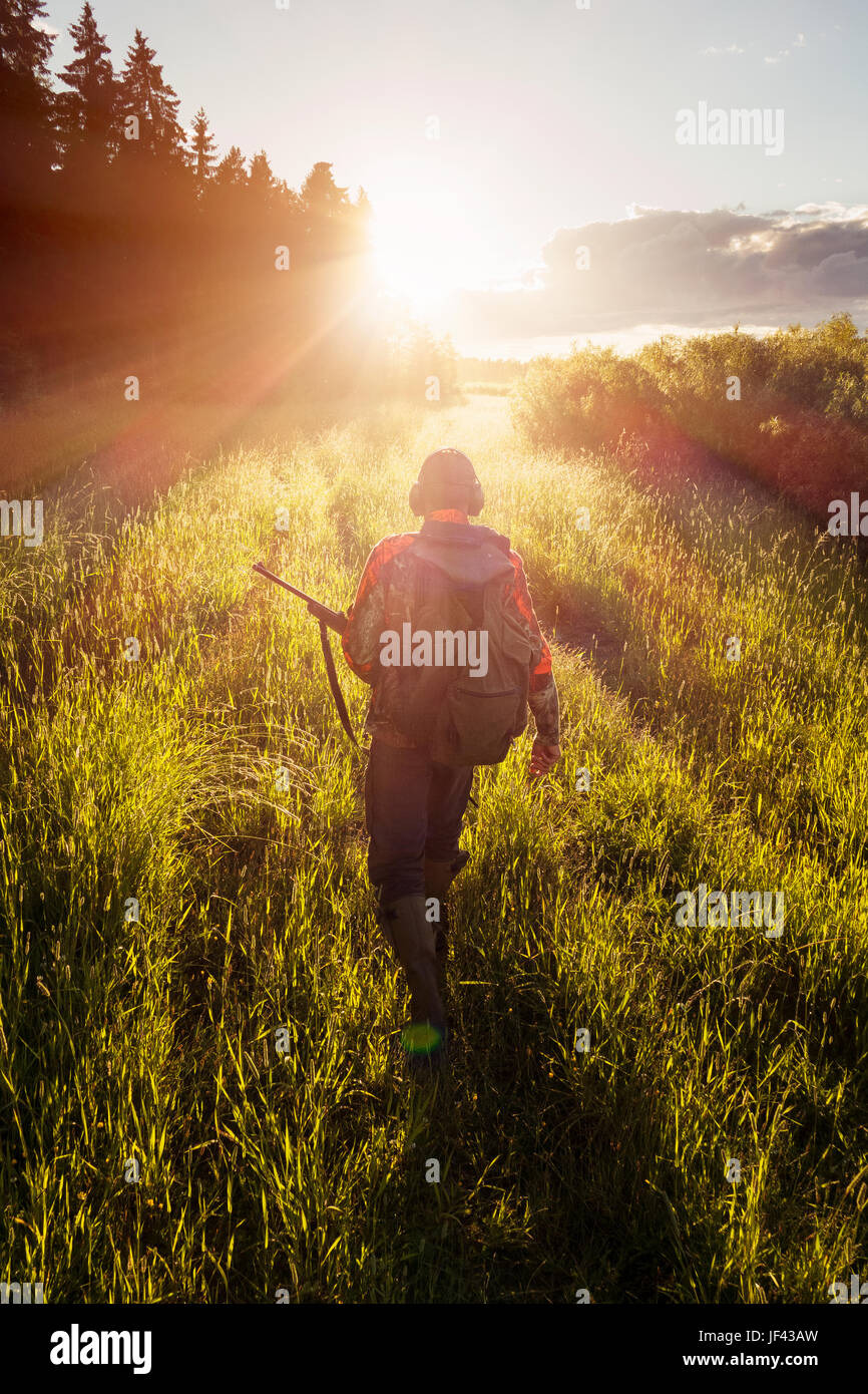 Hunter walking through meadow Stock Photo - Alamy