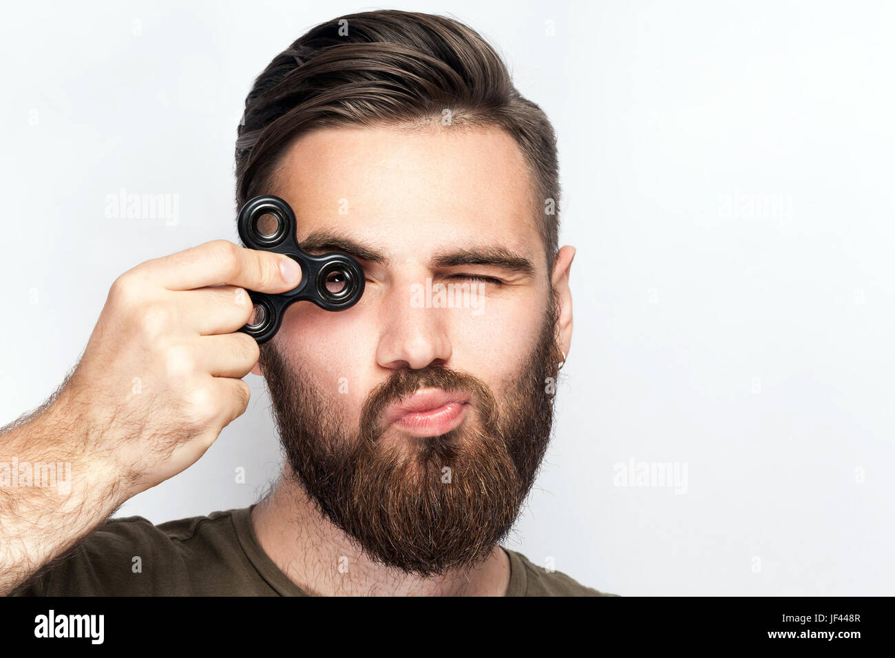 Young man holding and playing with fidget spinner. studio shot on white ...