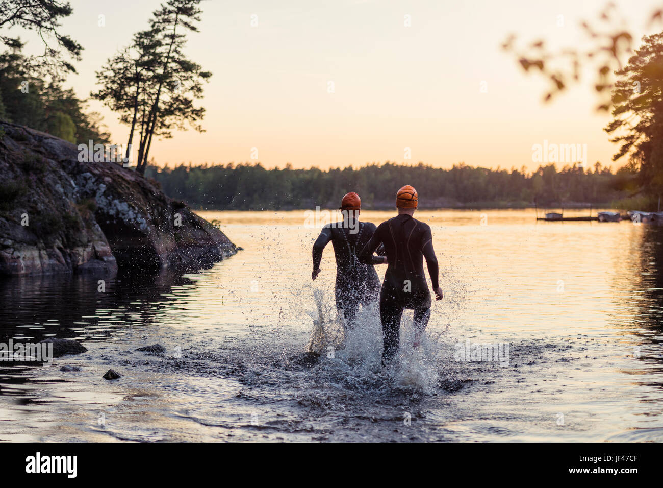 People running in water at sunset Stock Photo - Alamy