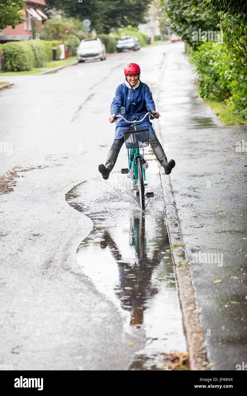 Woman riding bicycle through puddle Stock Photo - Alamy