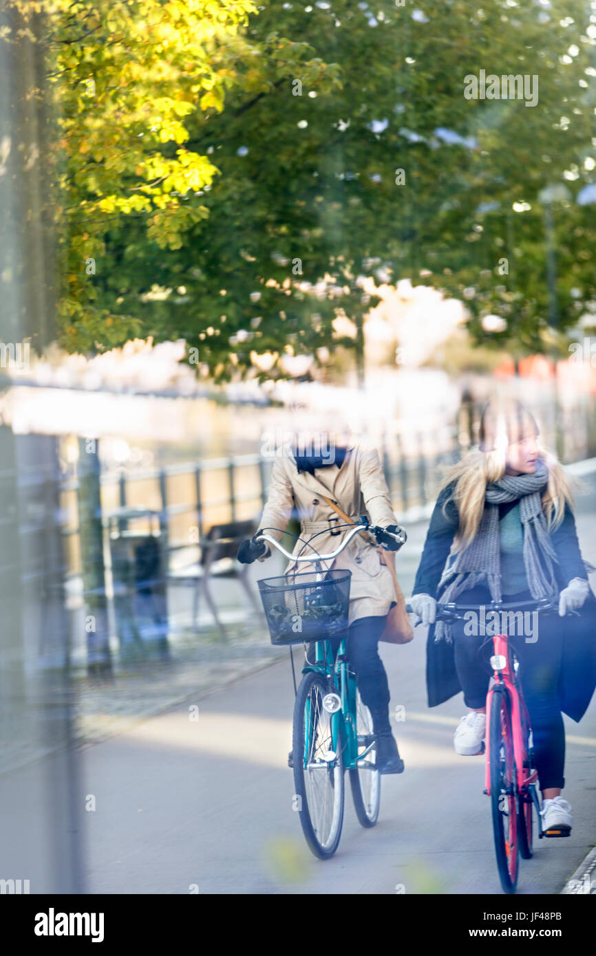 Women riding bicycles seen through window glass Stock Photo - Alamy