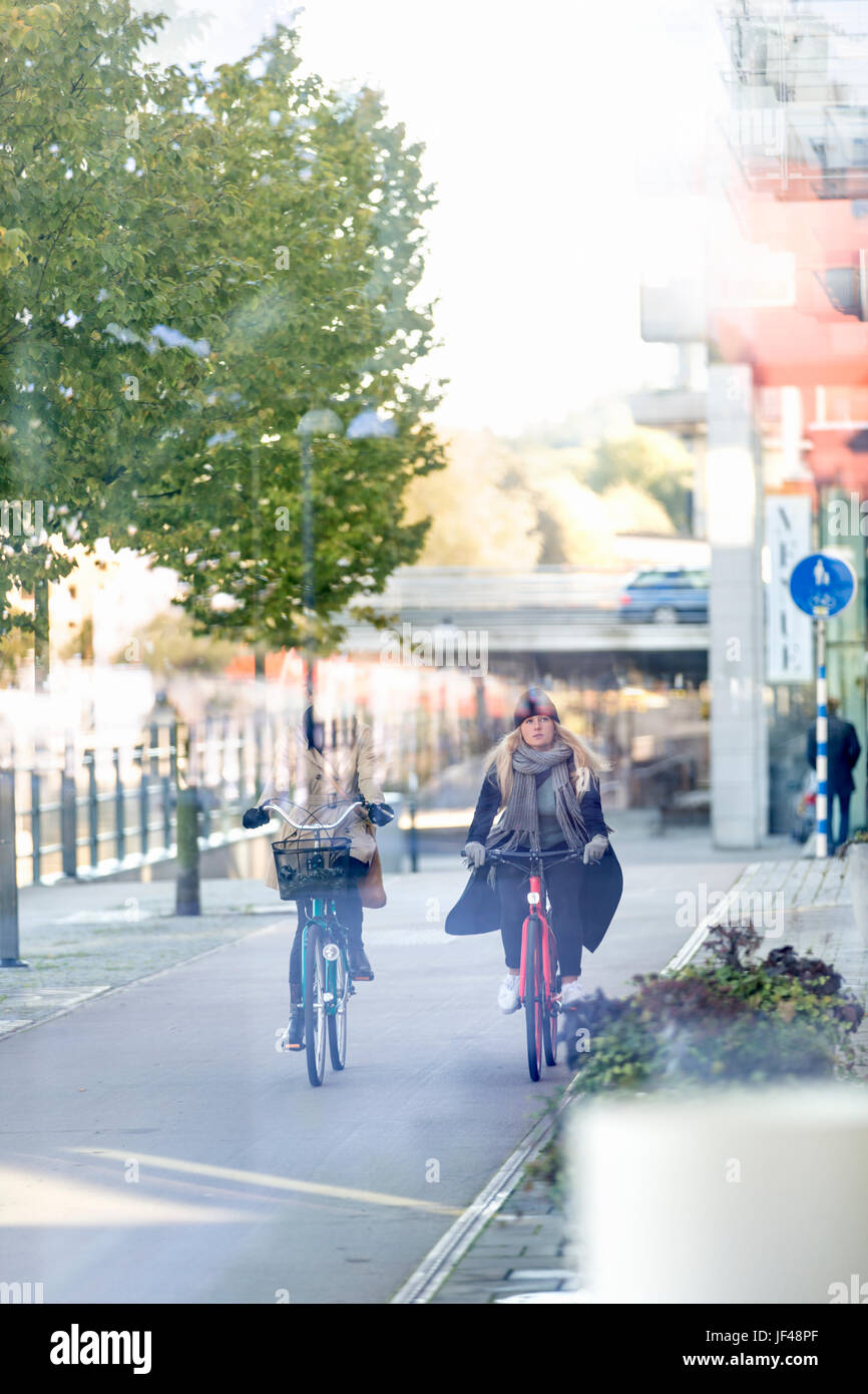 Women riding bicycles seen through window glass Stock Photo - Alamy