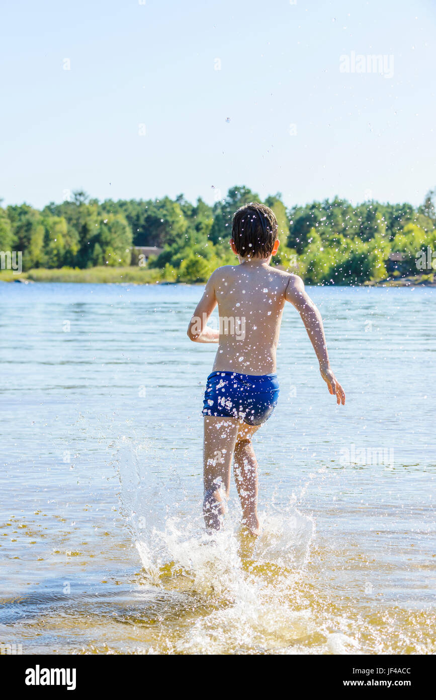 Boy running in water Stock Photo - Alamy