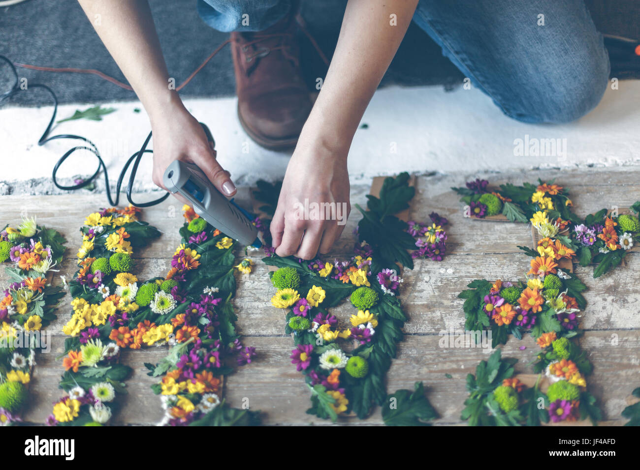 Florist making flower decoration with letters and glue. Indoors natural ...