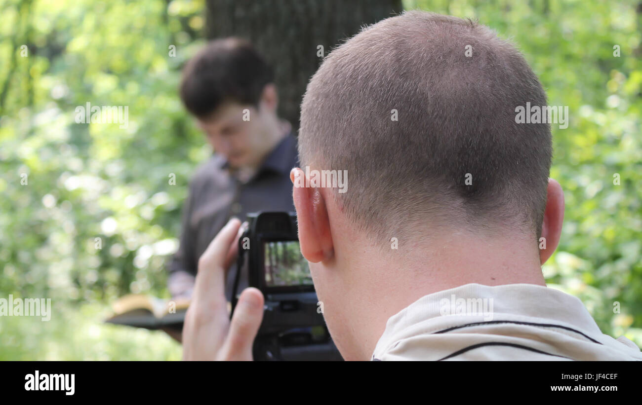 young businessman reading a book in the woods.the operator stands by ...