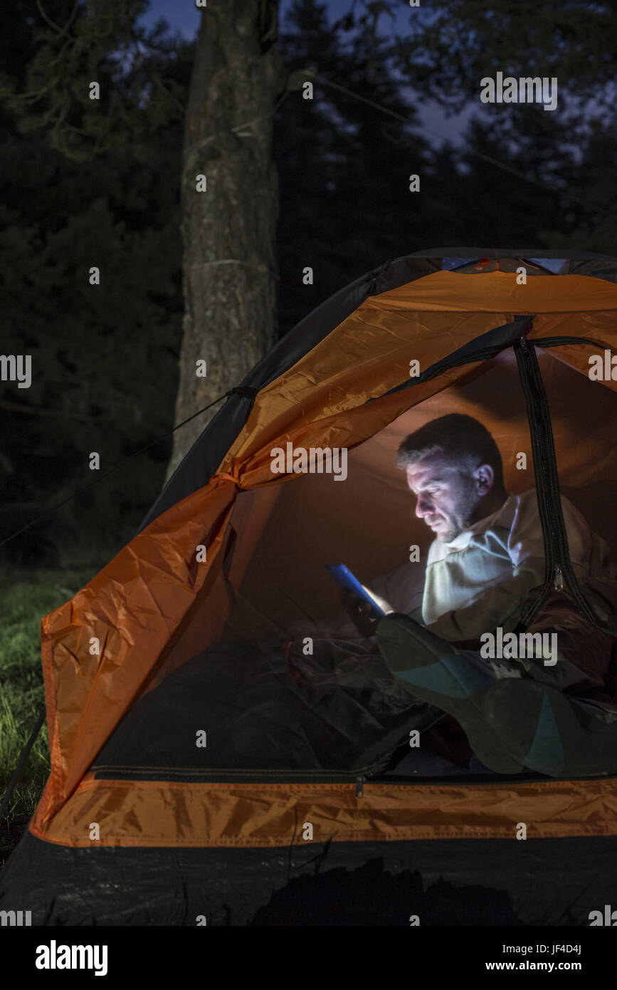 Man watching his smartphone in a tent Stock Photo - Alamy