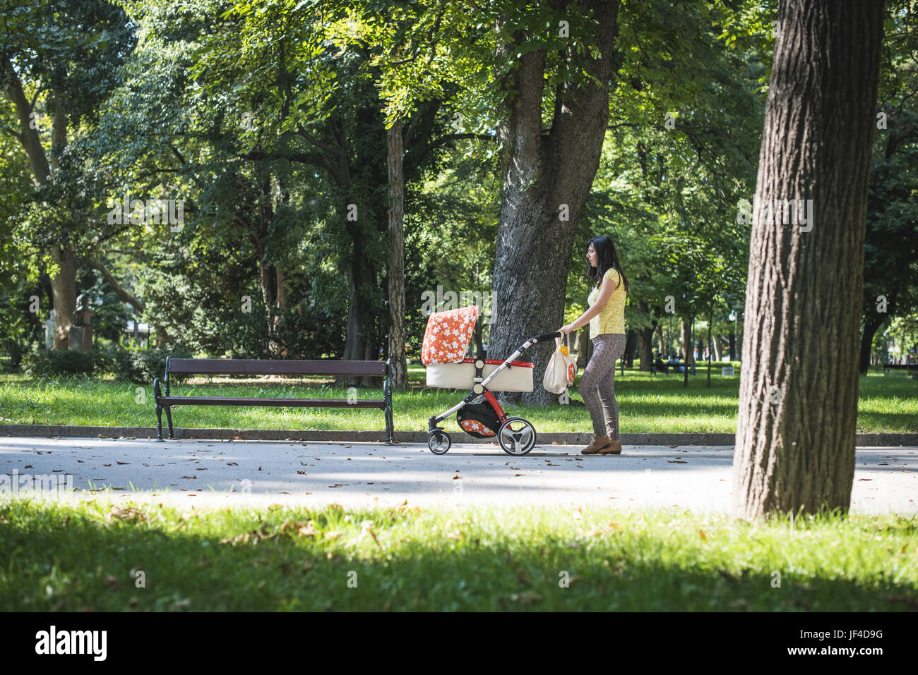 Mother walking in the park with baby buggy Stock Photo - Alamy