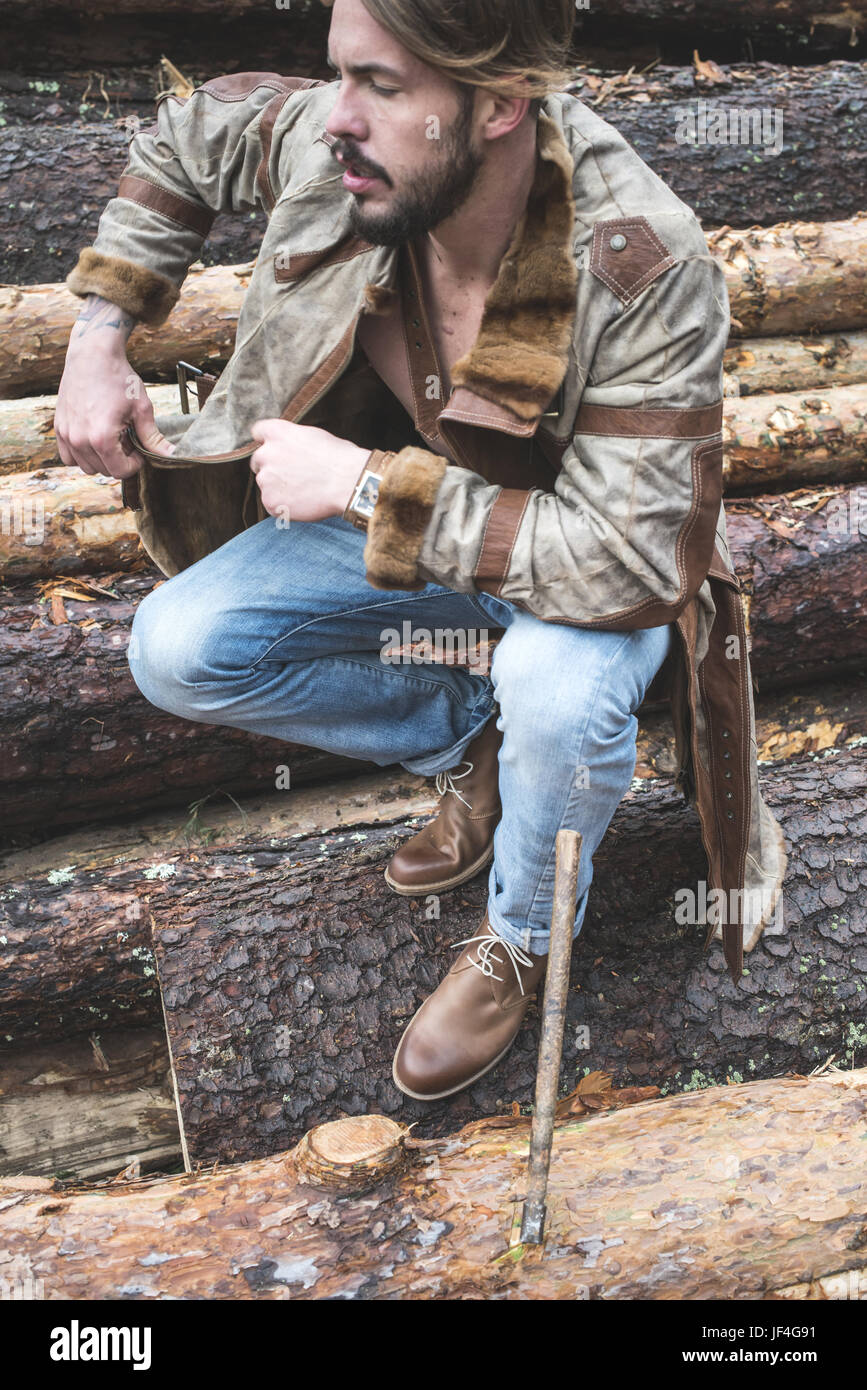 Young men on logs in the forest Stock Photo - Alamy