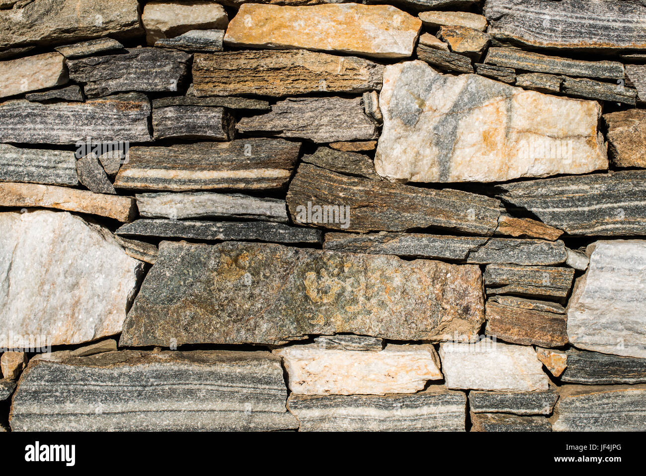 Wall built of stones. Sun light Stock Photo - Alamy